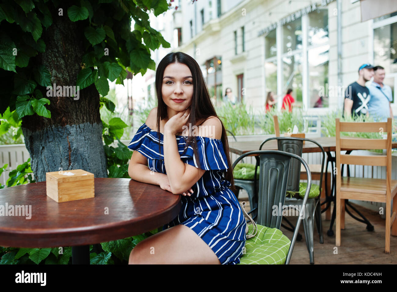 Gorgeous brunette girl sitting on the table in cafe Stock Photo - Alamy
