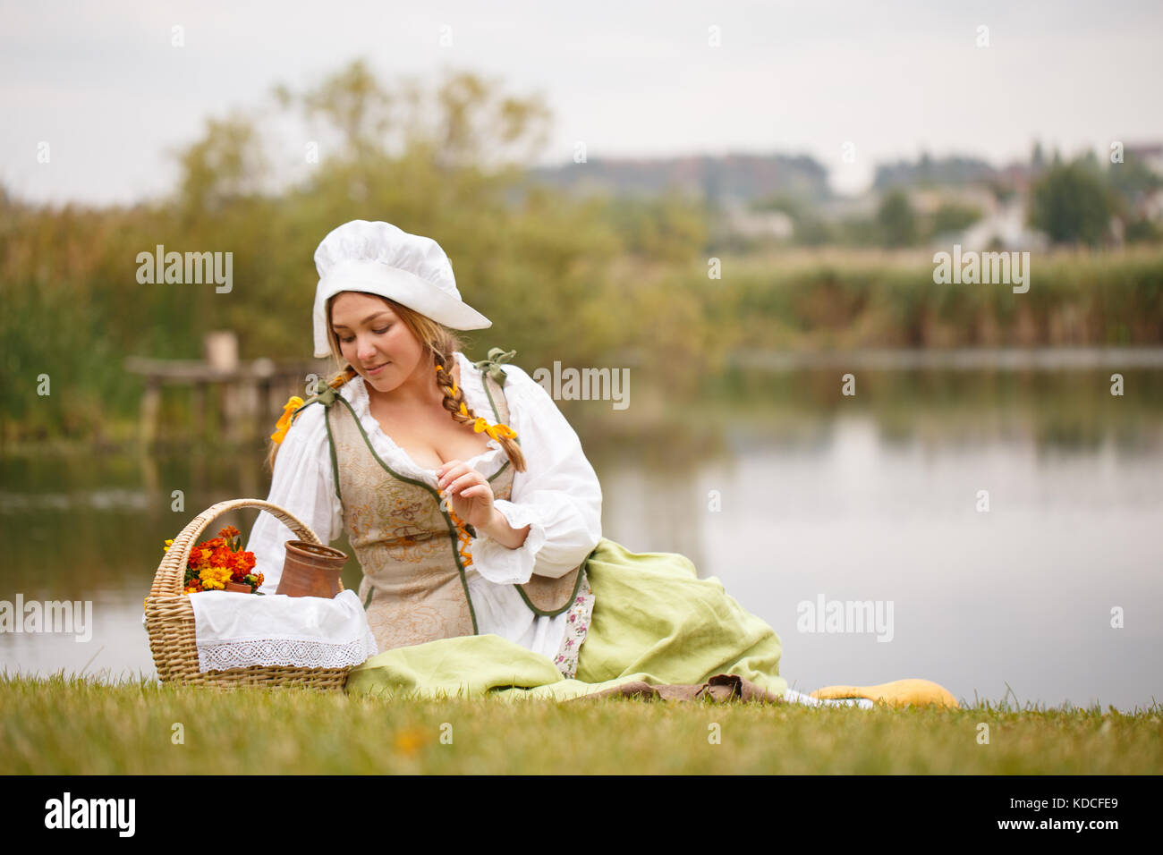 pretty peasant woman with a basket sits by the river Stock Photo - Alamy