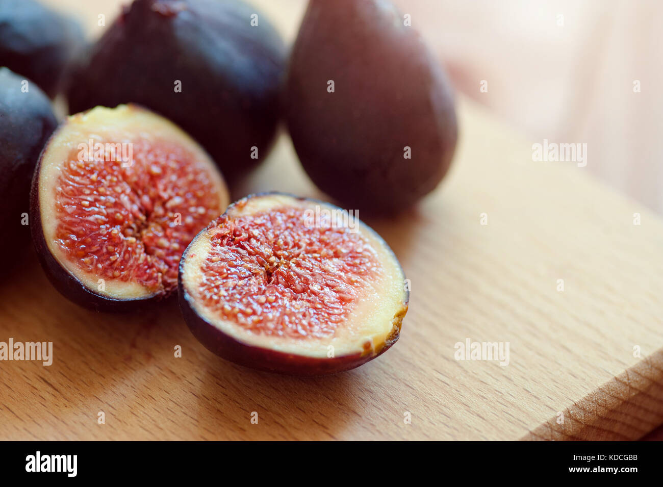 Whole figs and one fig sliced in half on top of a teak garden table ...