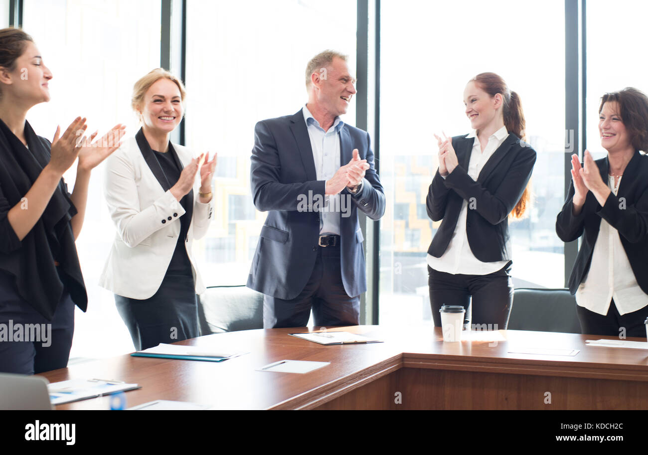 Business people group clapping and smiling in office standing around ...