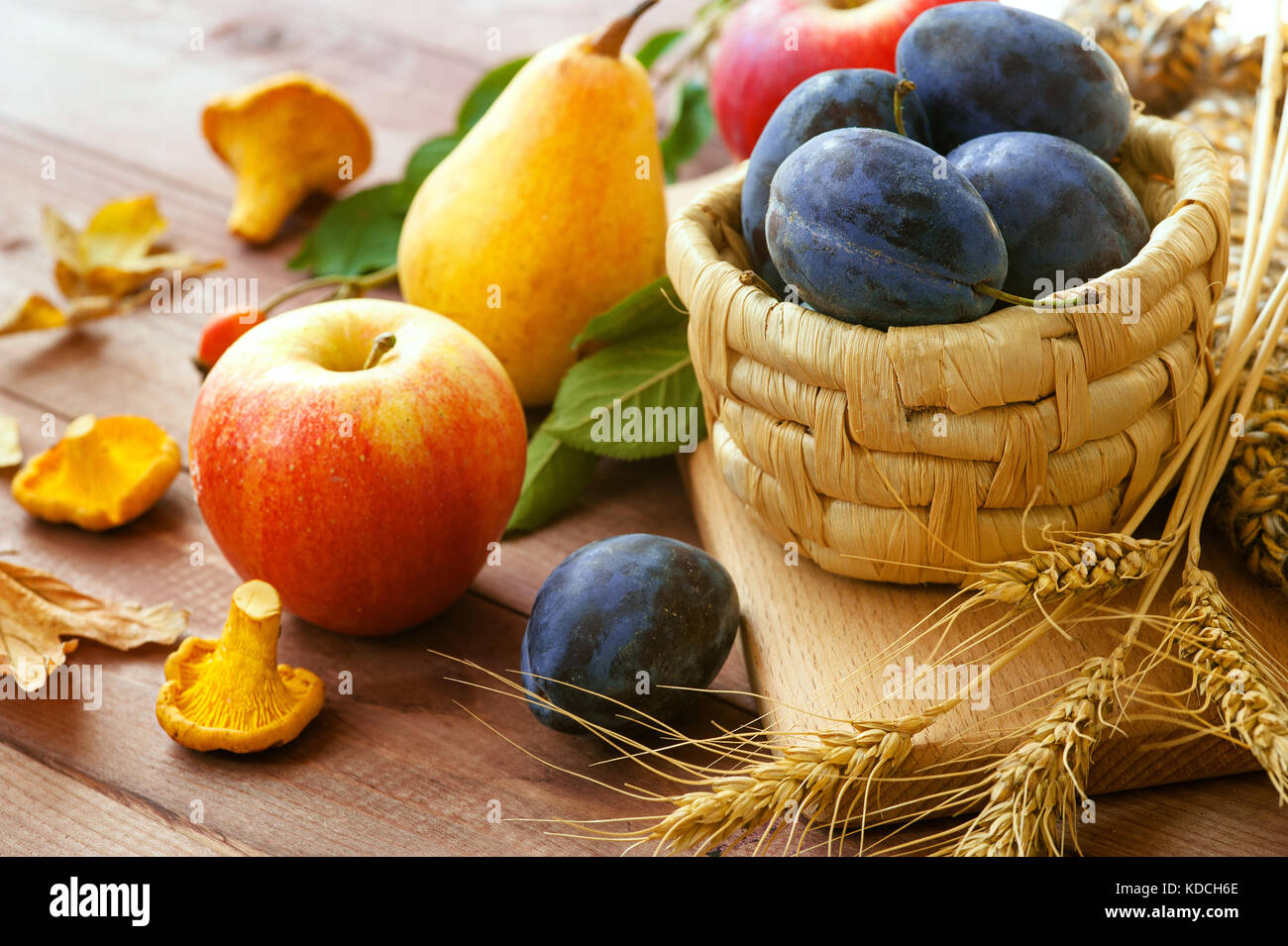 Fresh ripe pears, plums and apples in bowl on natural background ...