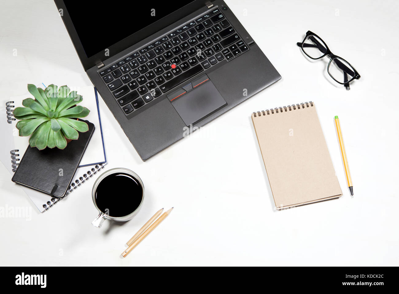 Top view of white office desktop with laptop keyboard, plant, coffee ...
