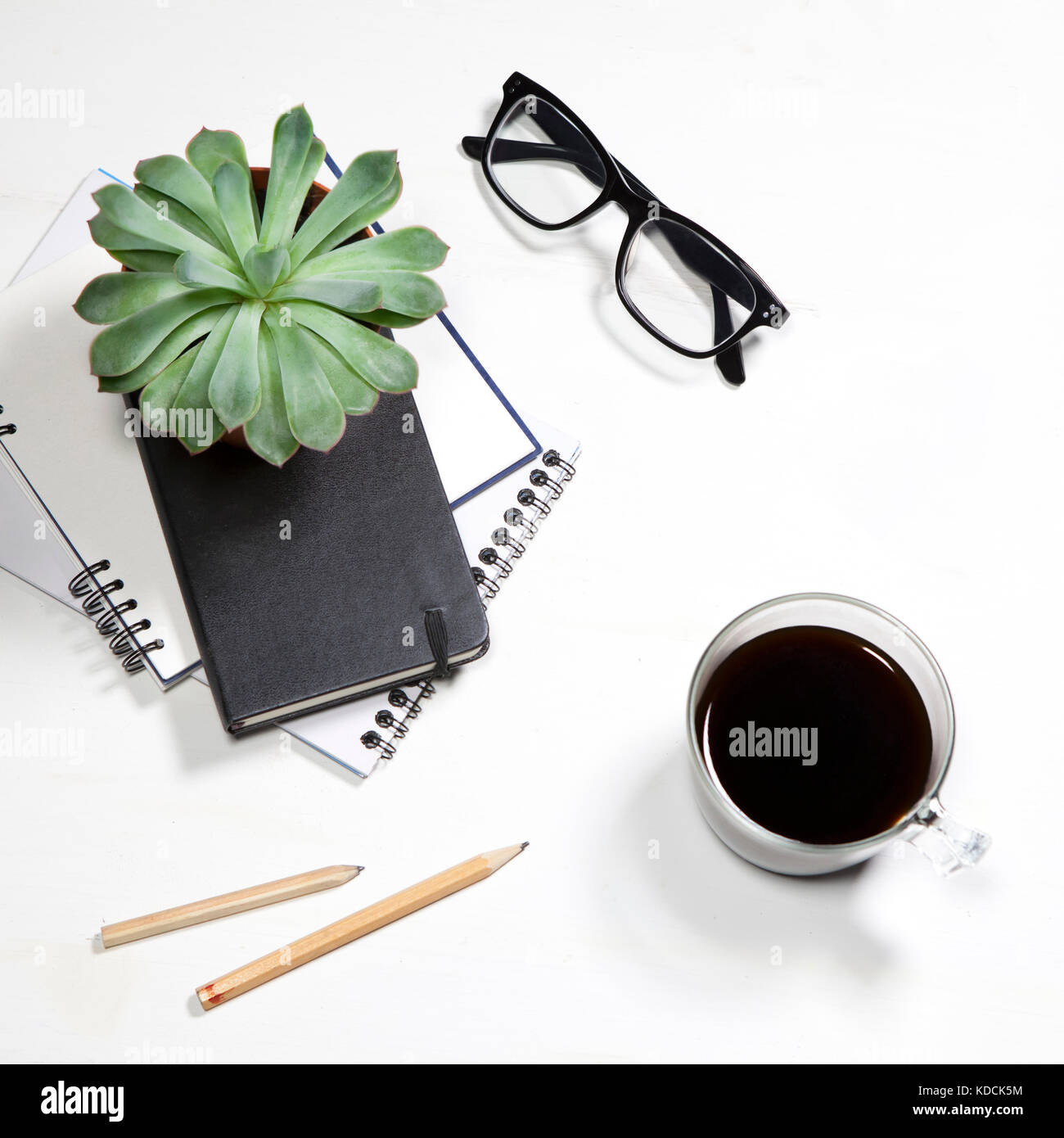 Top view of white office desktop with plant, coffee cup, glasses and ...