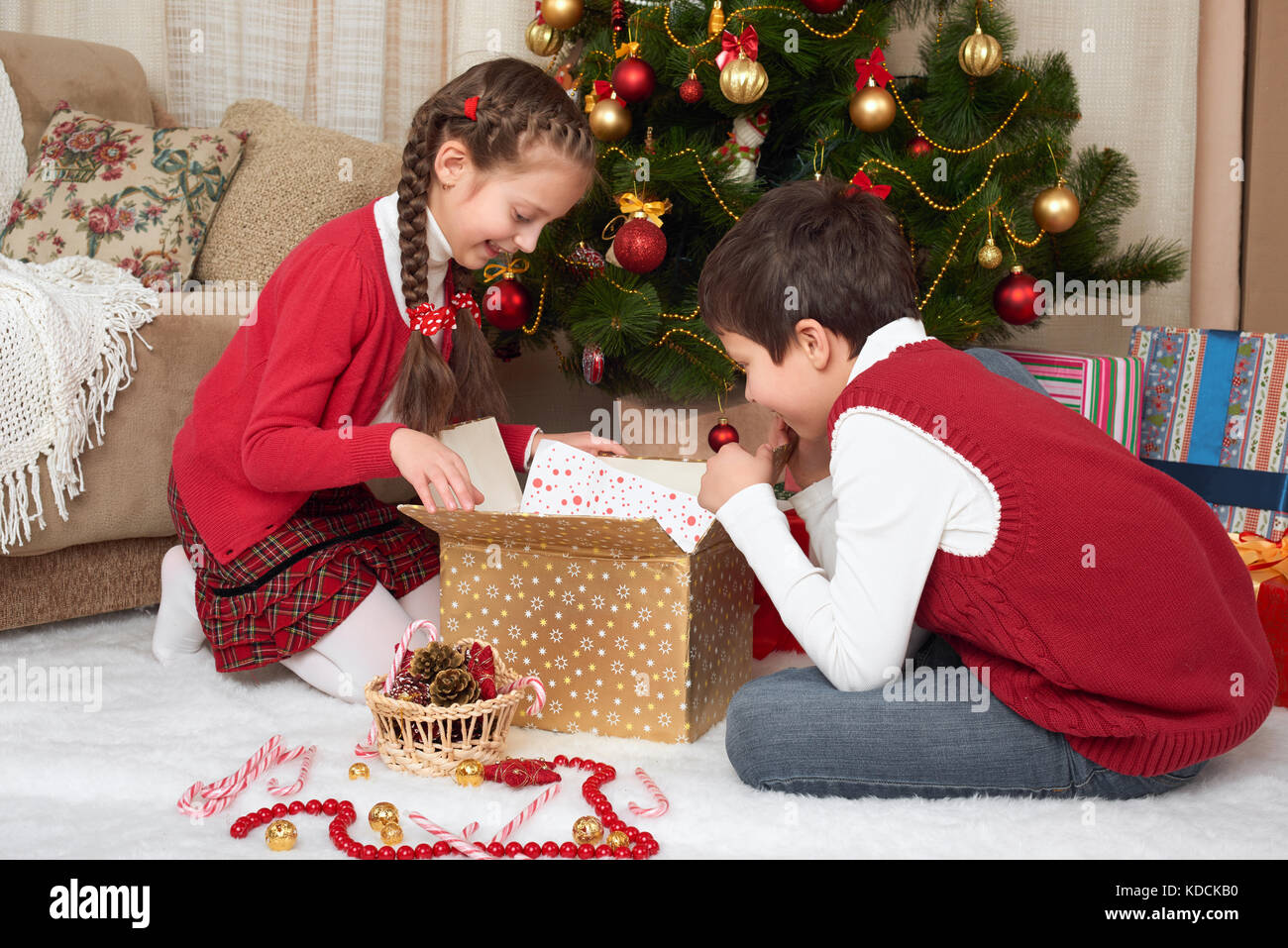 Child unpack gift boxes near christmas tree, decoration at home, happy ...