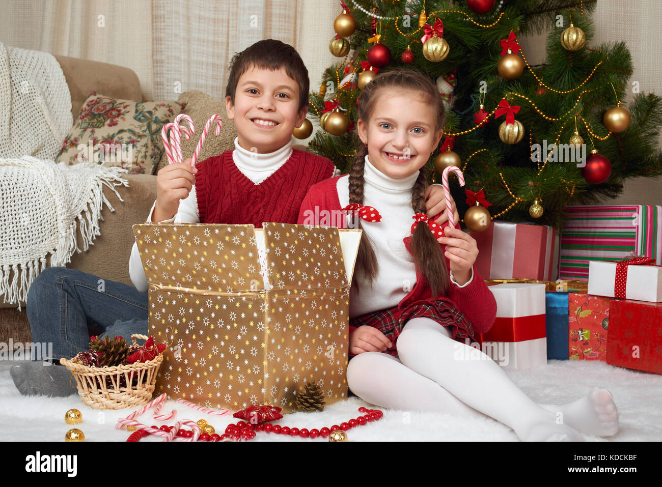 Child unpack gift boxes near christmas tree, decoration at home, happy ...