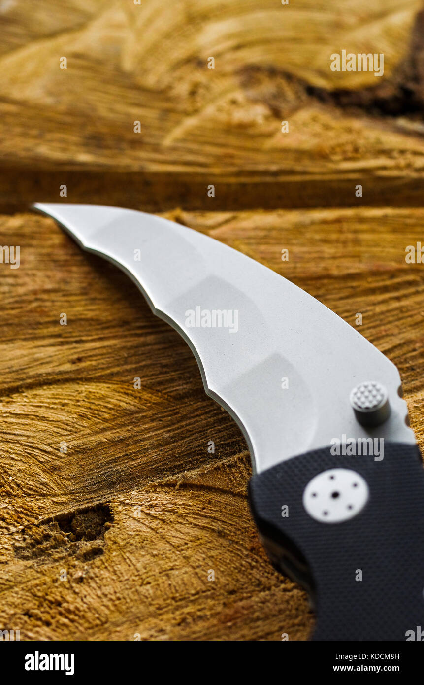 Knife blade in the form of a fang. Natural background of wood Stock ...