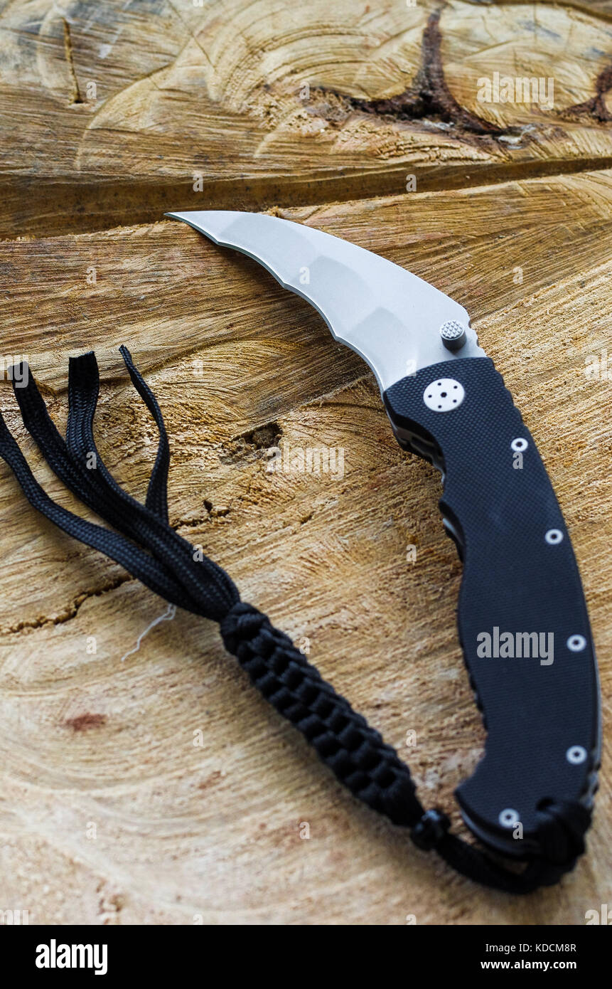 Knife in the form of a claw. Vertical shot. Natural background of wood ...