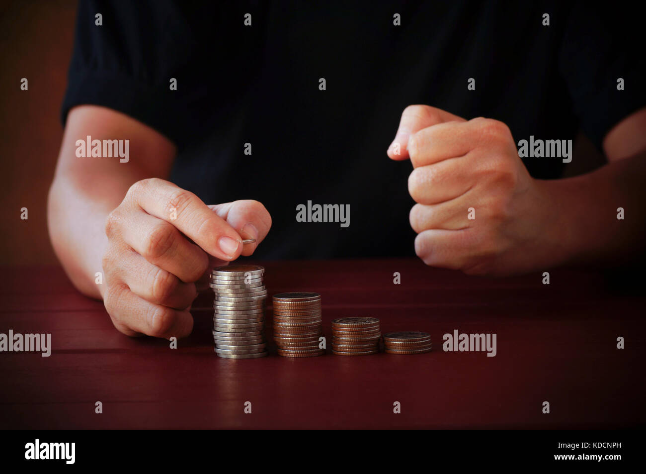 man put money on pile of coins Stock Photo - Alamy