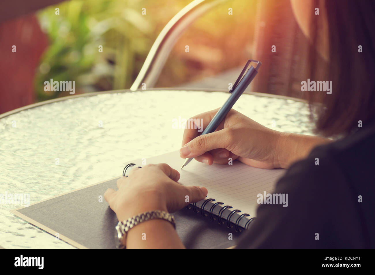 female student writing in notebook on table Stock Photo - Alamy