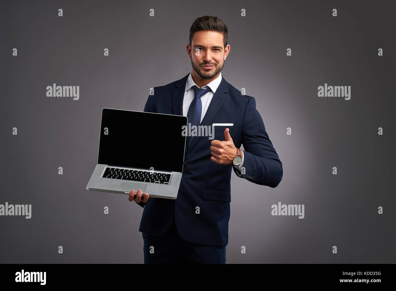 An elegant handsome young man holding and showing the screen of a ...