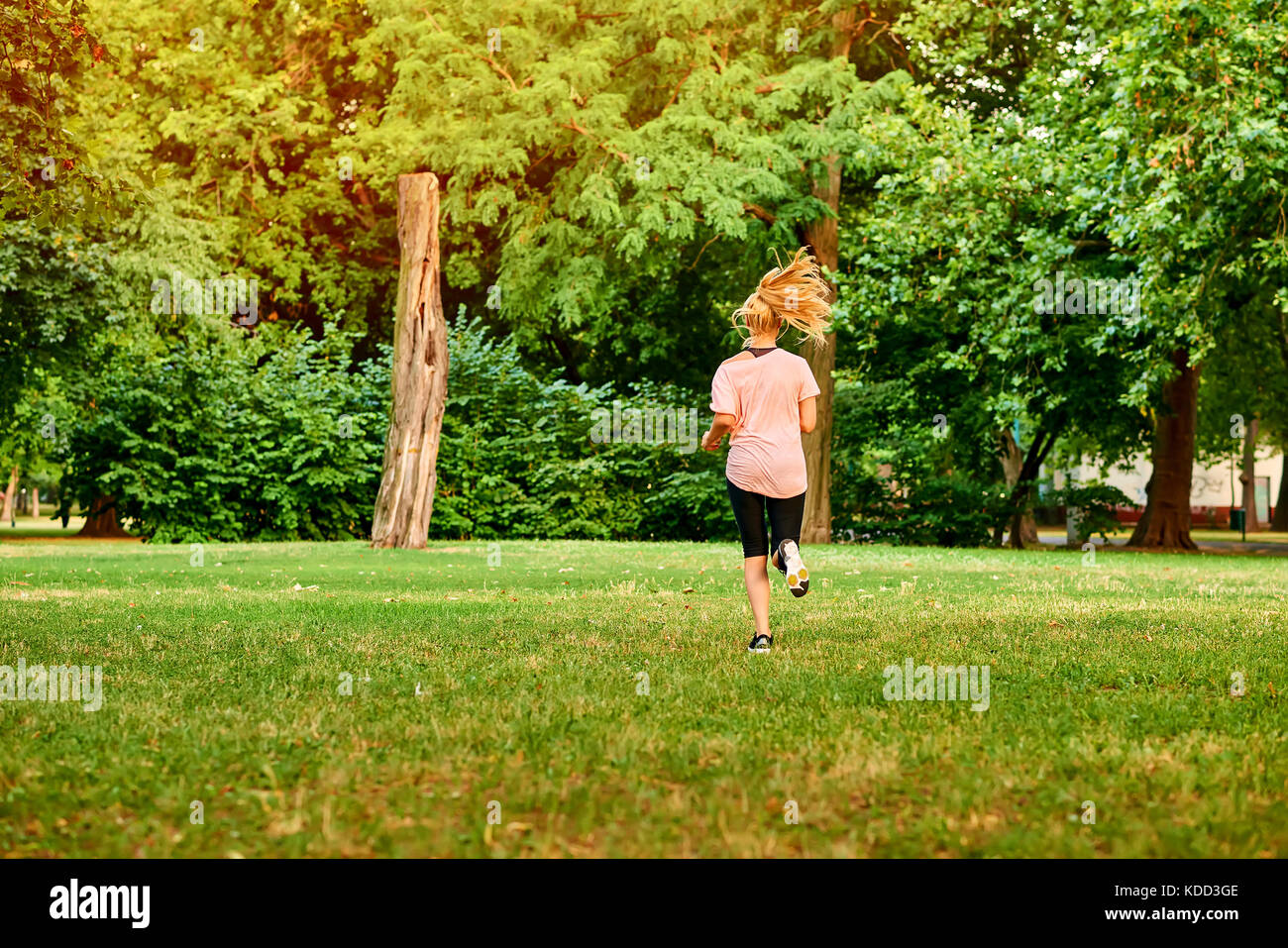 A beautiful young blond woman running away from the camera through a ...