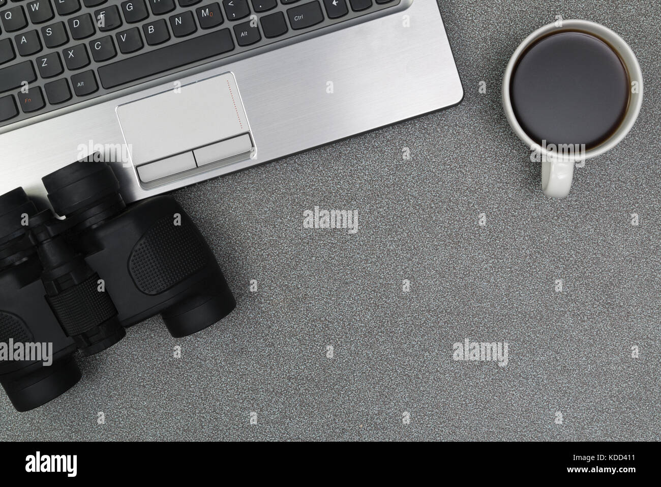 Laptop computer or notebook, binocular and cup of coffee on gray color ...