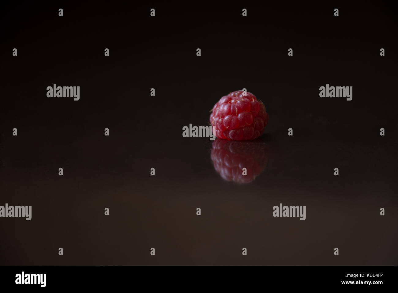 Close up of a raspberry resting on a black surface upside down Stock ...