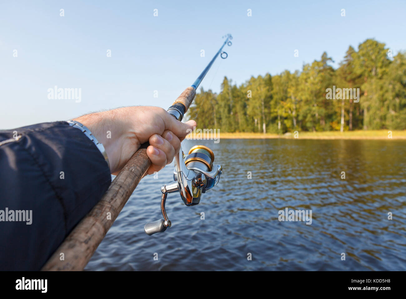 Fishing on a lake. Fishing rod with a reel in hand. Vew of the shore ...