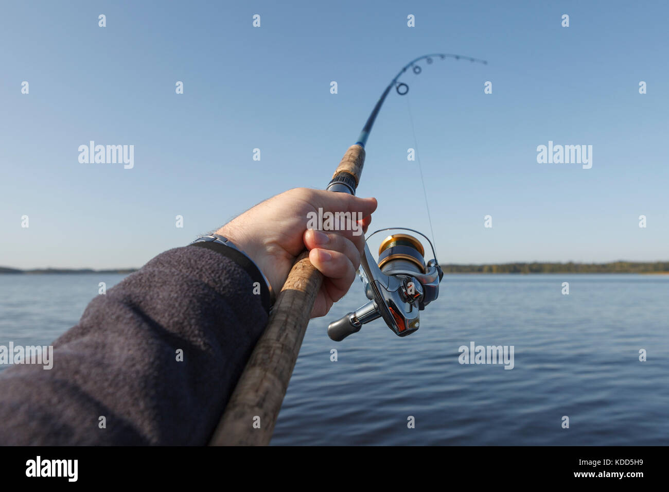Fishing on a lake. Fishing rod with a reel in hand.clear blue sky Stock ...
