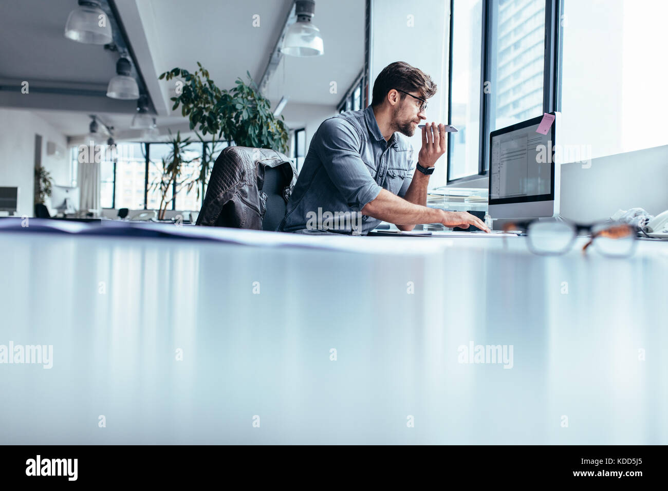 Male executive working on computer and talking on mobile phone ...
