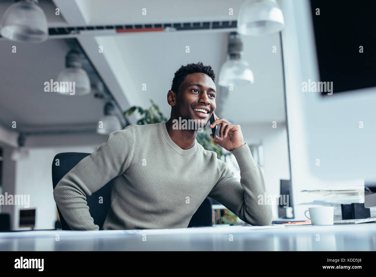 Portrait of male executive making phone call while sitting in office ...