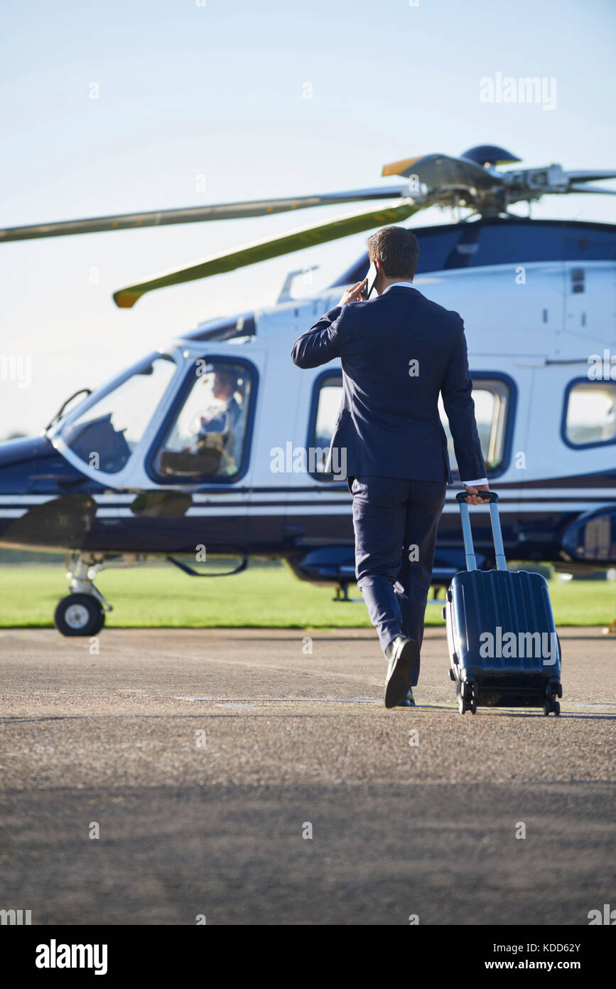 Businessman Walking Towards Helicopter Whilst Talking On Mobile Phone ...