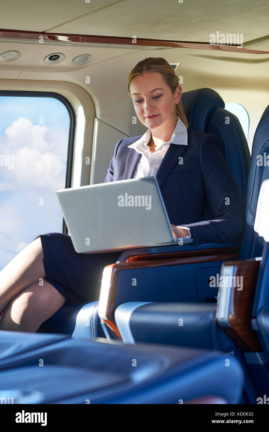 Businesswoman Working On Laptop In Helicopter Cabin During Flight Stock ...