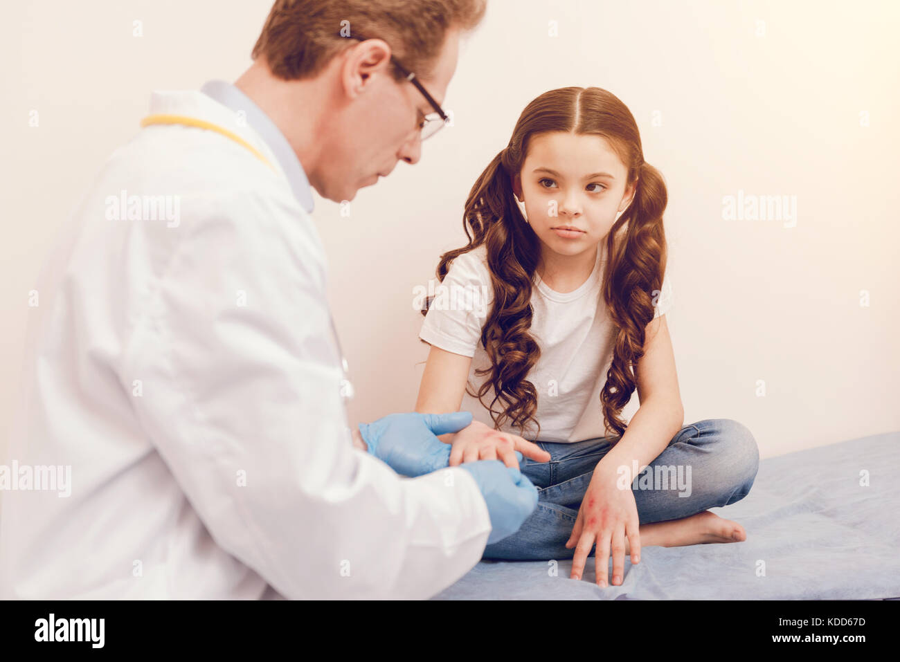 Upset kid crossing legs while being in consulting room Stock Photo - Alamy