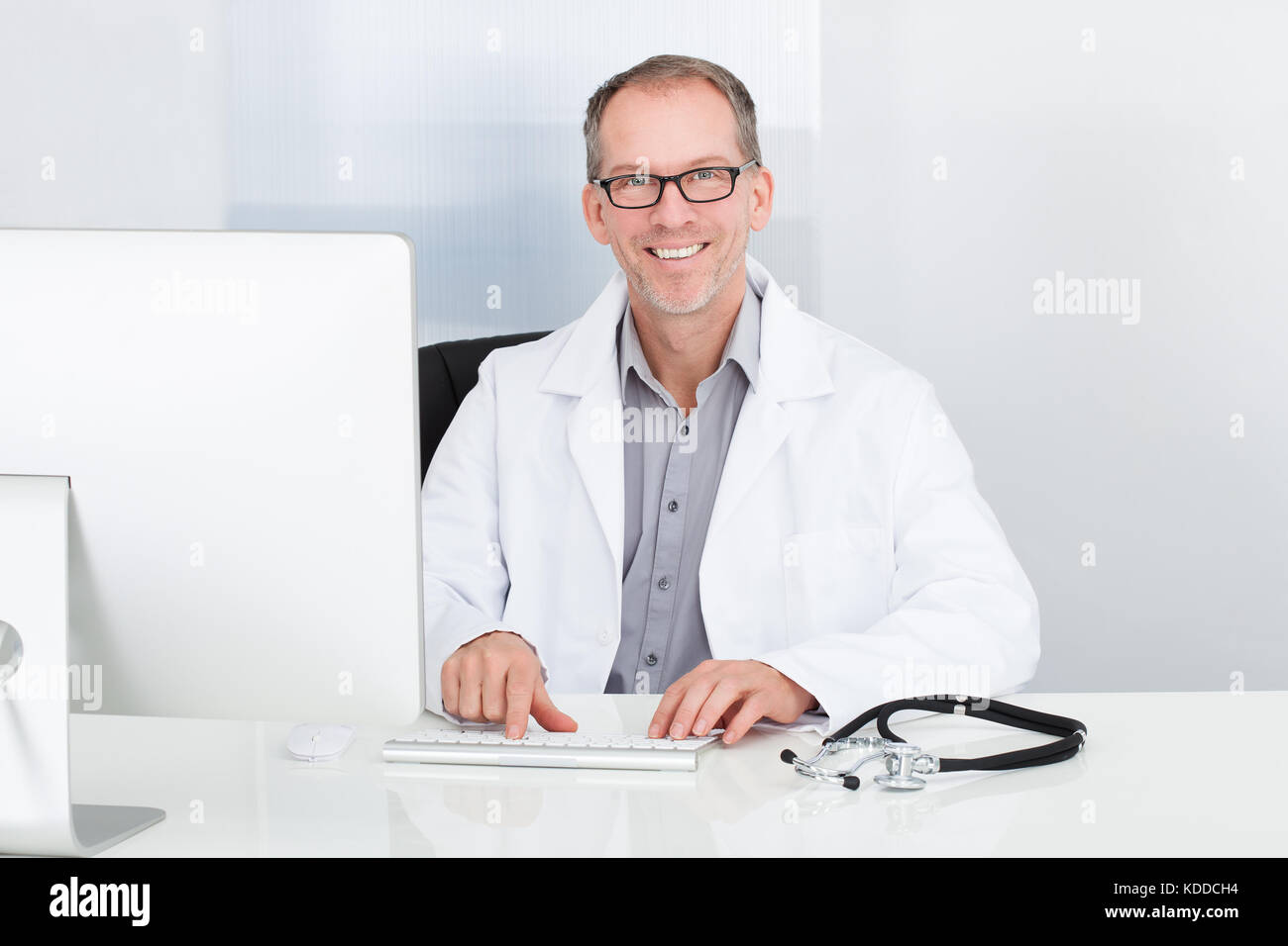 Portrait Of Happy Mature Doctor Using Computer In Clinic Stock Photo ...