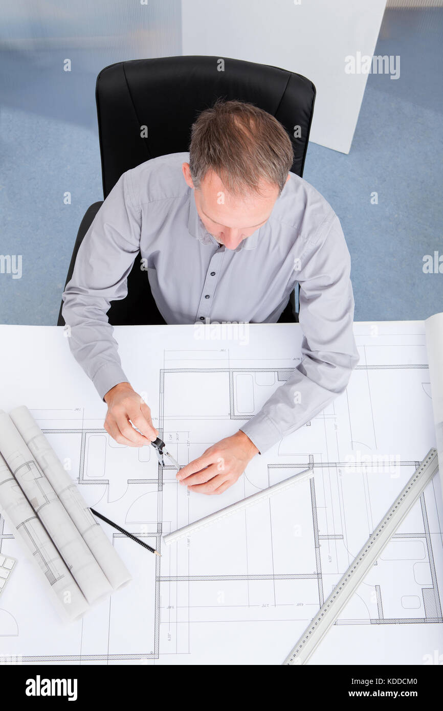 Portrait Of A Mature Architect Drawing Plan On Blueprint In Office ...