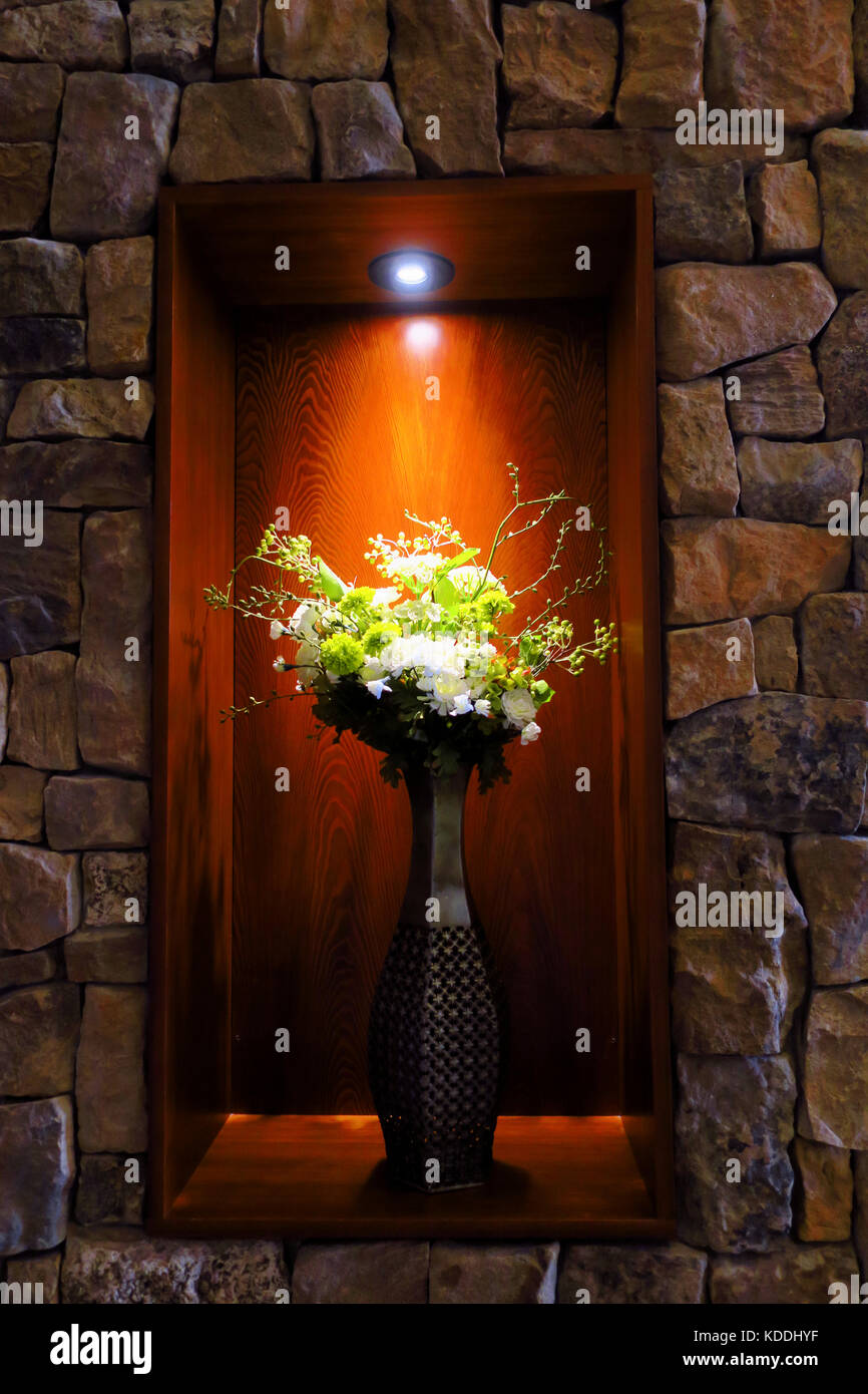 A plant in a fancy pot on display in a little nook set in maghony wood ...
