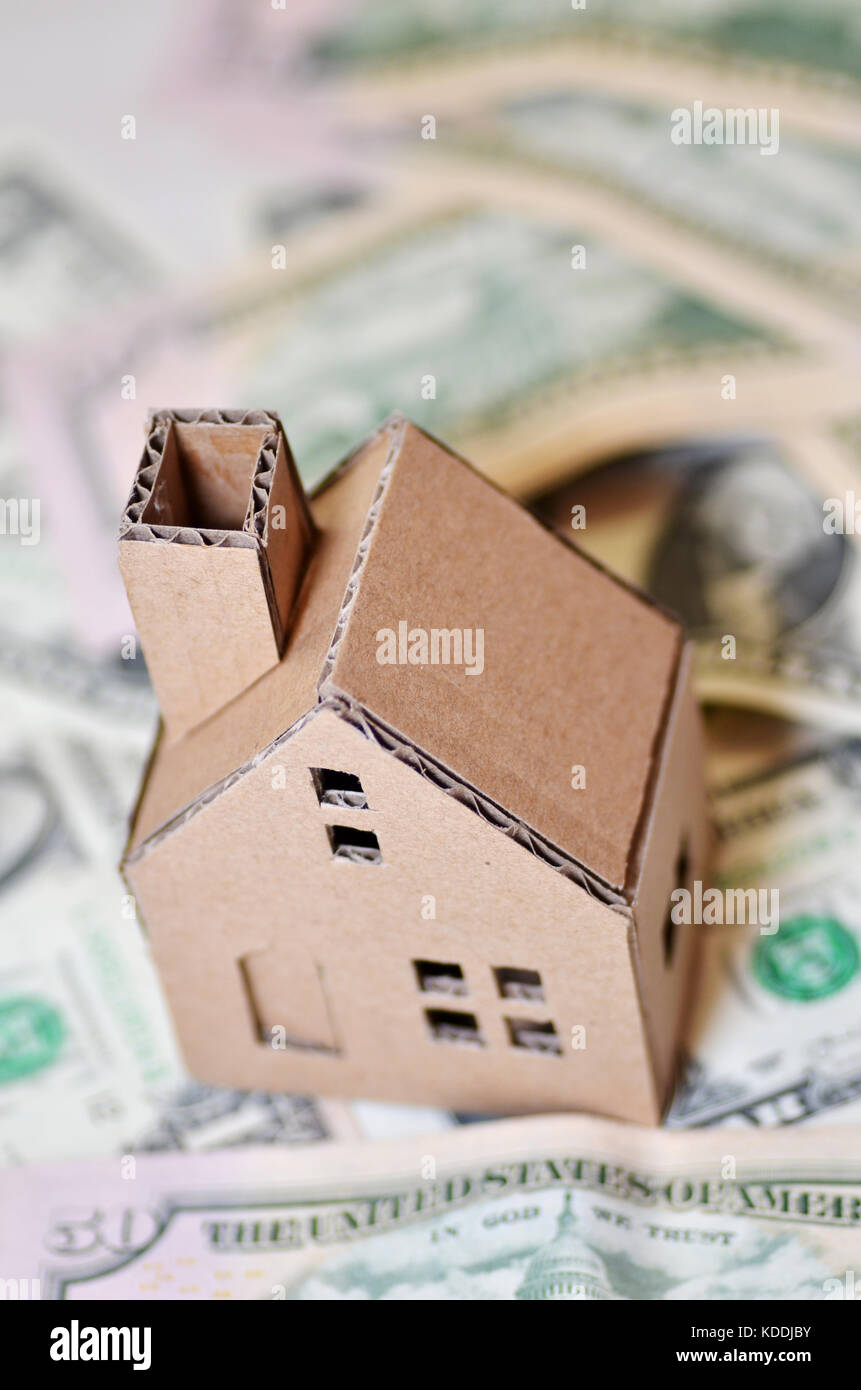Paper made house stands on dollar money Stock Photo - Alamy