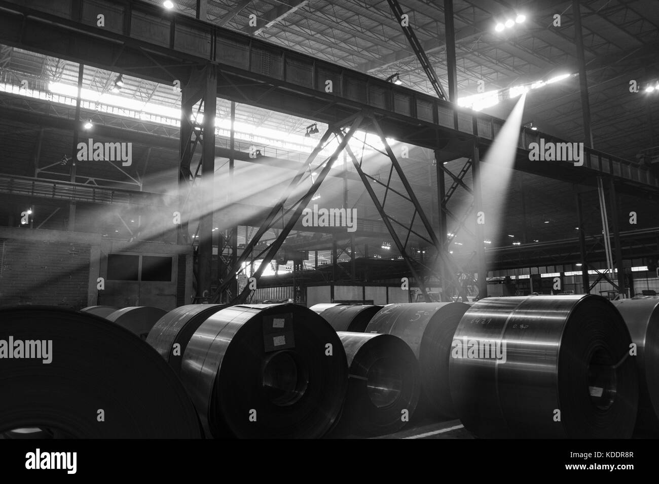 Sun beams bursting through the roof windows of a steel mill shining on ...