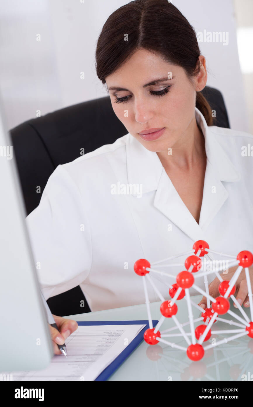 Female Scientist Sitting In Laboratory And Writing On Clipboard Stock ...