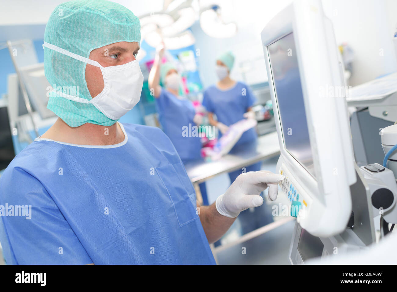 doctor or surgeon examinig screen of sophisticated medical equipment ...