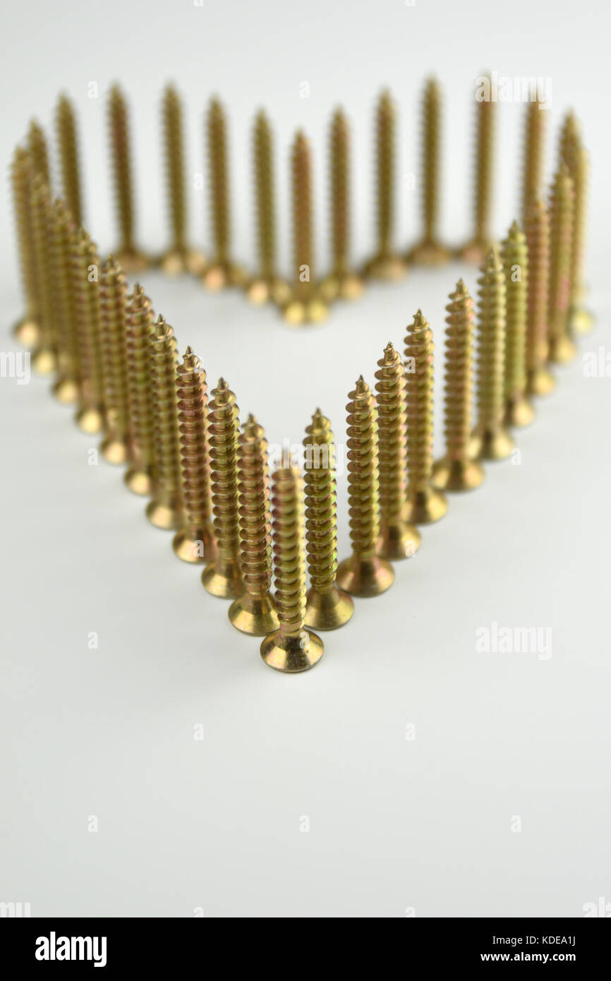 Love heart made from standing brass screws on white background Stock ...