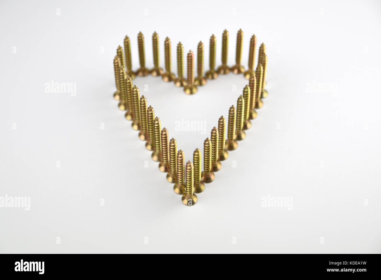 Love heart made from standing brass screws on white background Stock ...