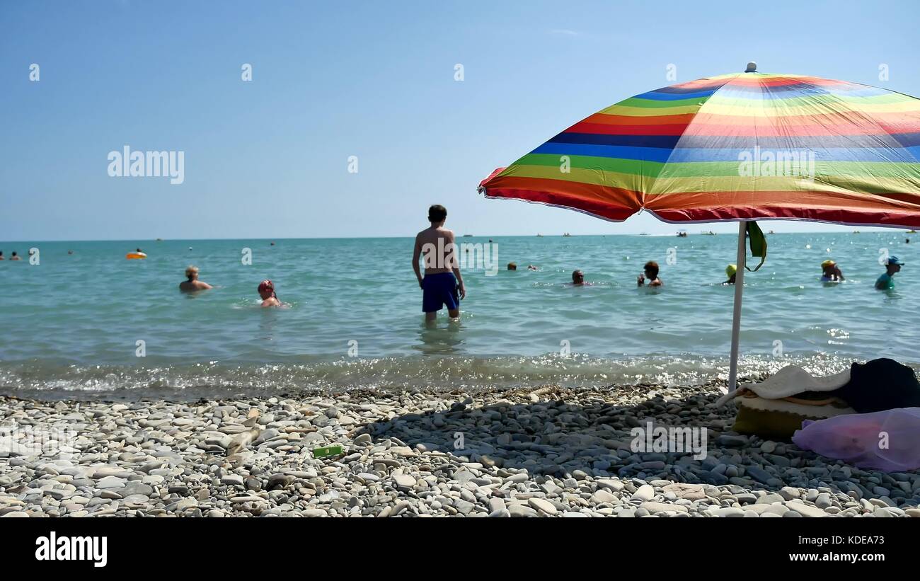 People bathing in the sun, swimming and playing games on the beach ...