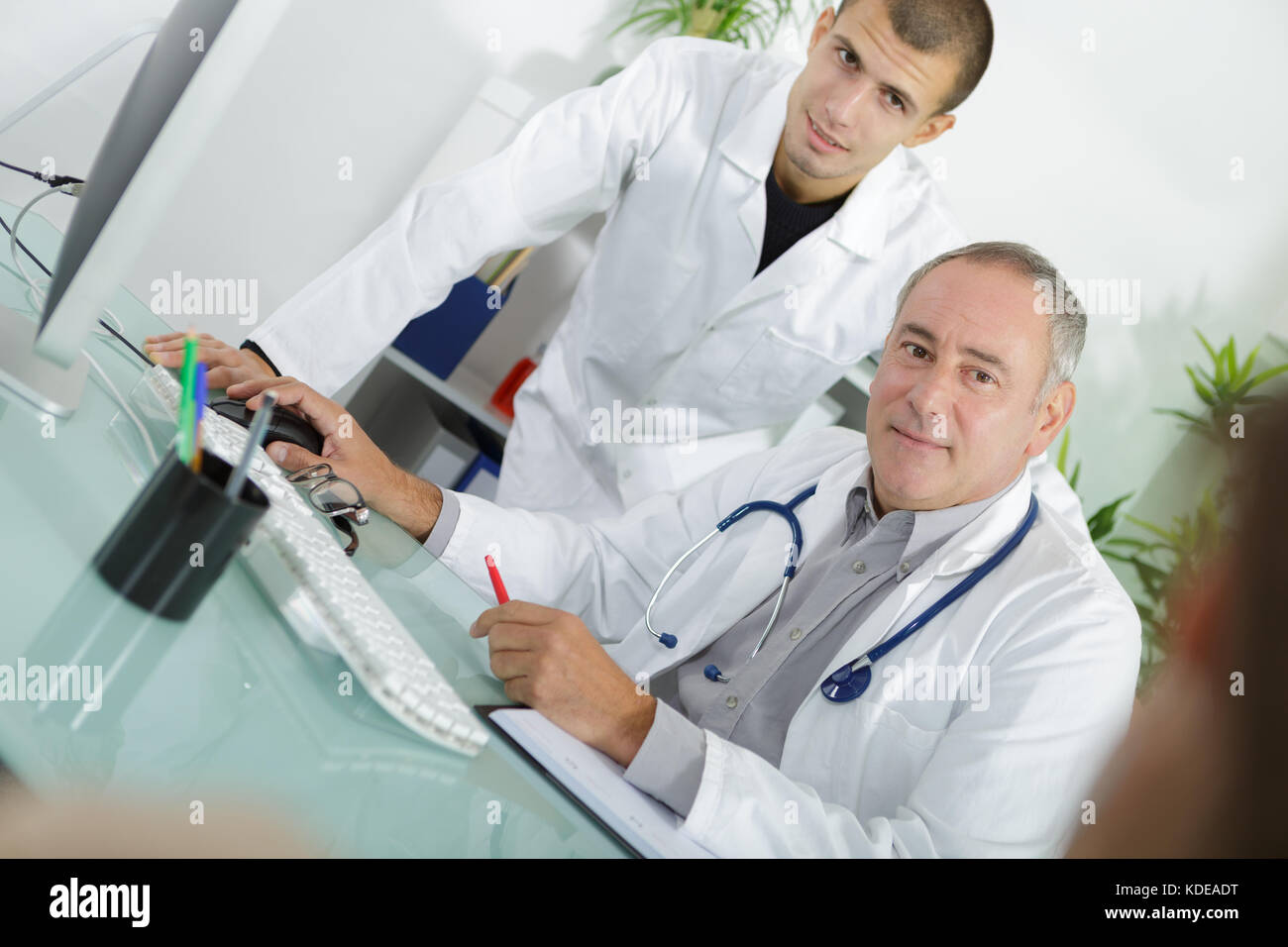 doctor talking to a patient with his young assistant Stock Photo - Alamy
