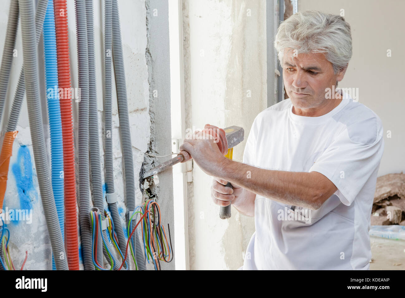 Builder using hammer and chisel on wall Stock Photo - Alamy