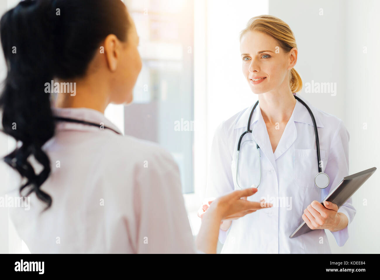 Cheerful young doctor listening to colleague at hospital Stock Photo ...