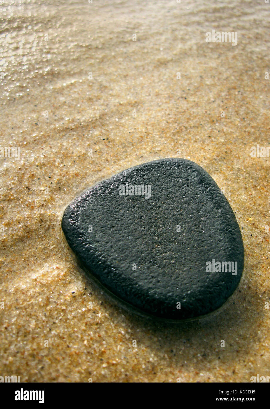 Black pebble on the sand of the beach after the surf Stock Photo - Alamy