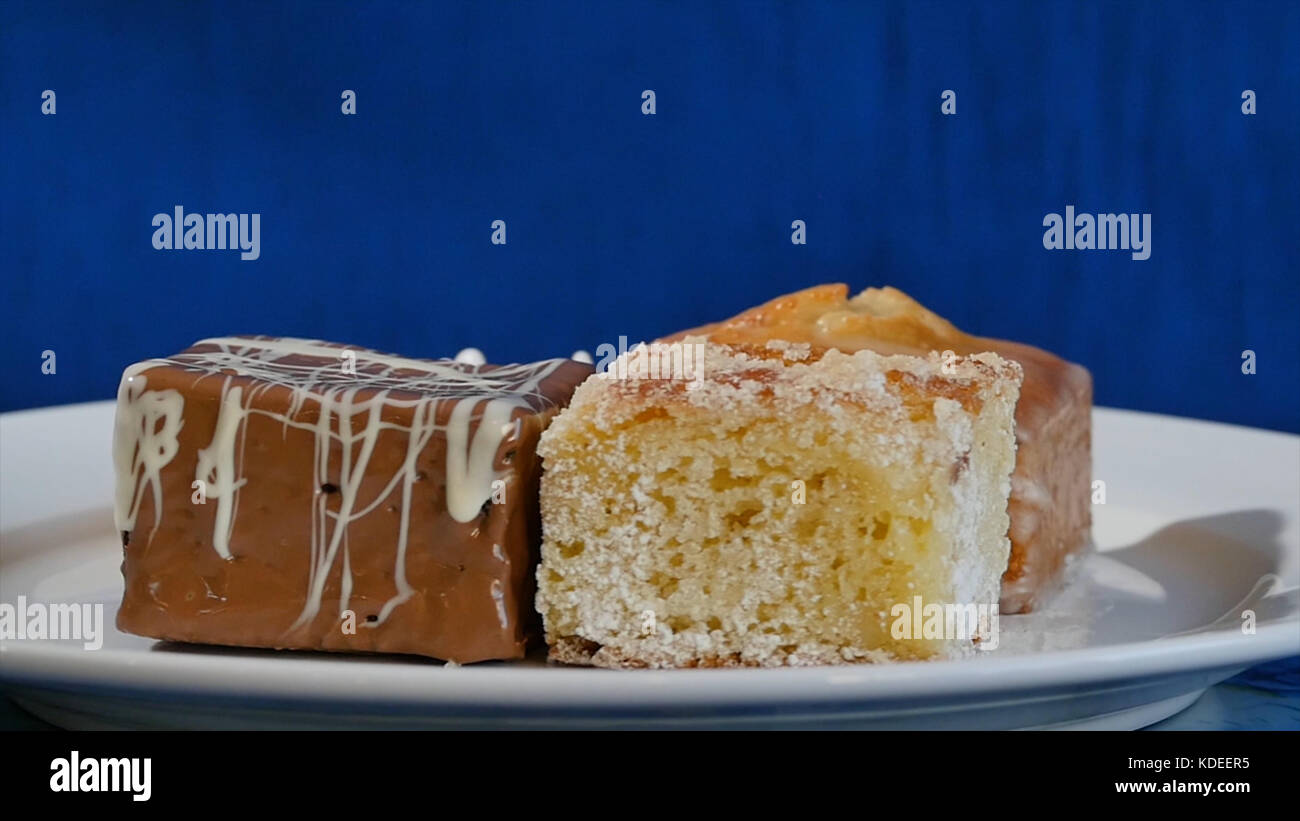 Cakes with cherry on a white plate on wooden boards. different pastries ...