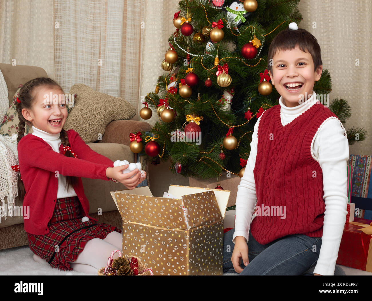 Child unpack gift boxes near christmas tree, show a handful of snow ...