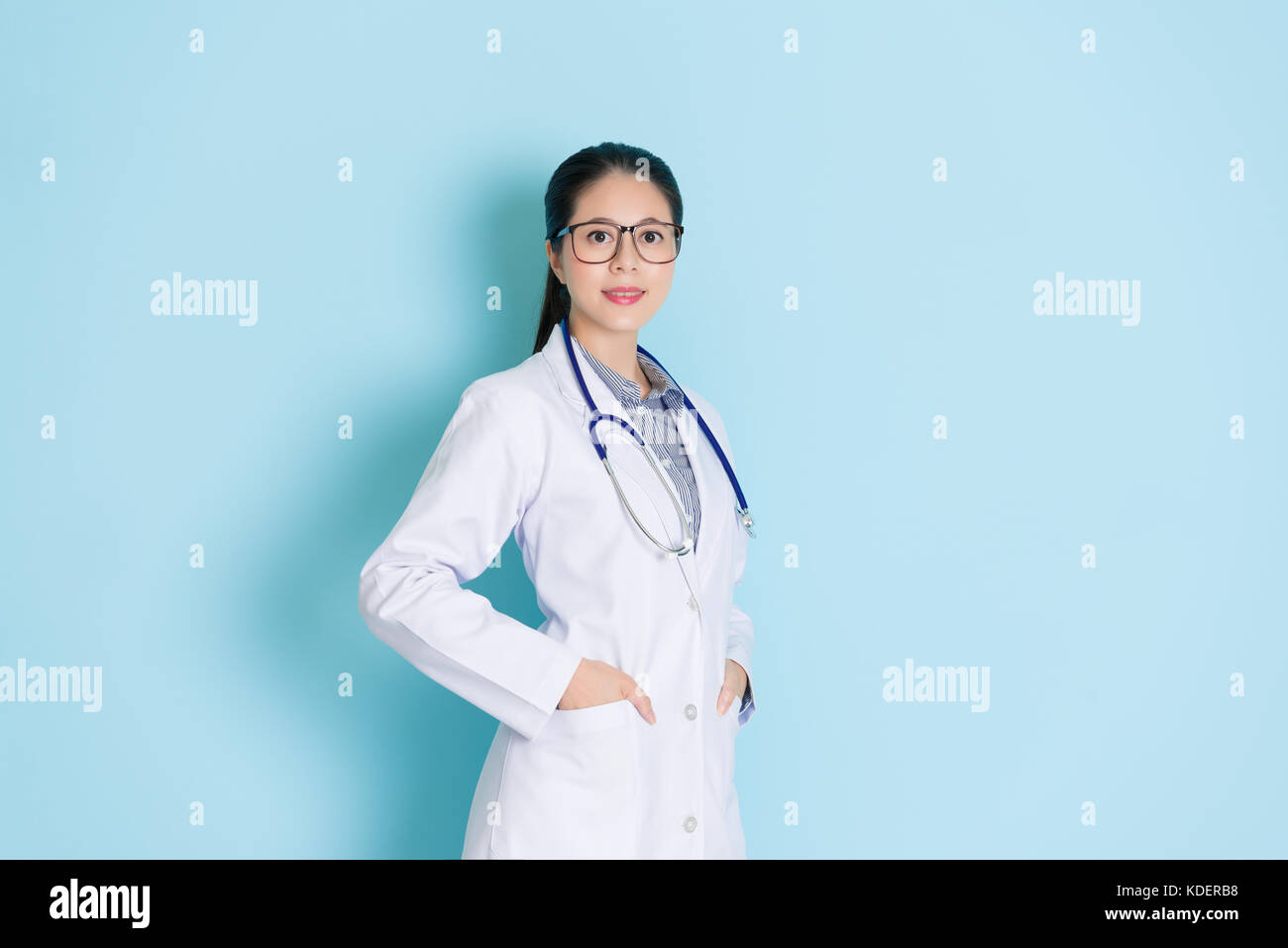 beautiful professional female clinic doctor standing in blue wall ...