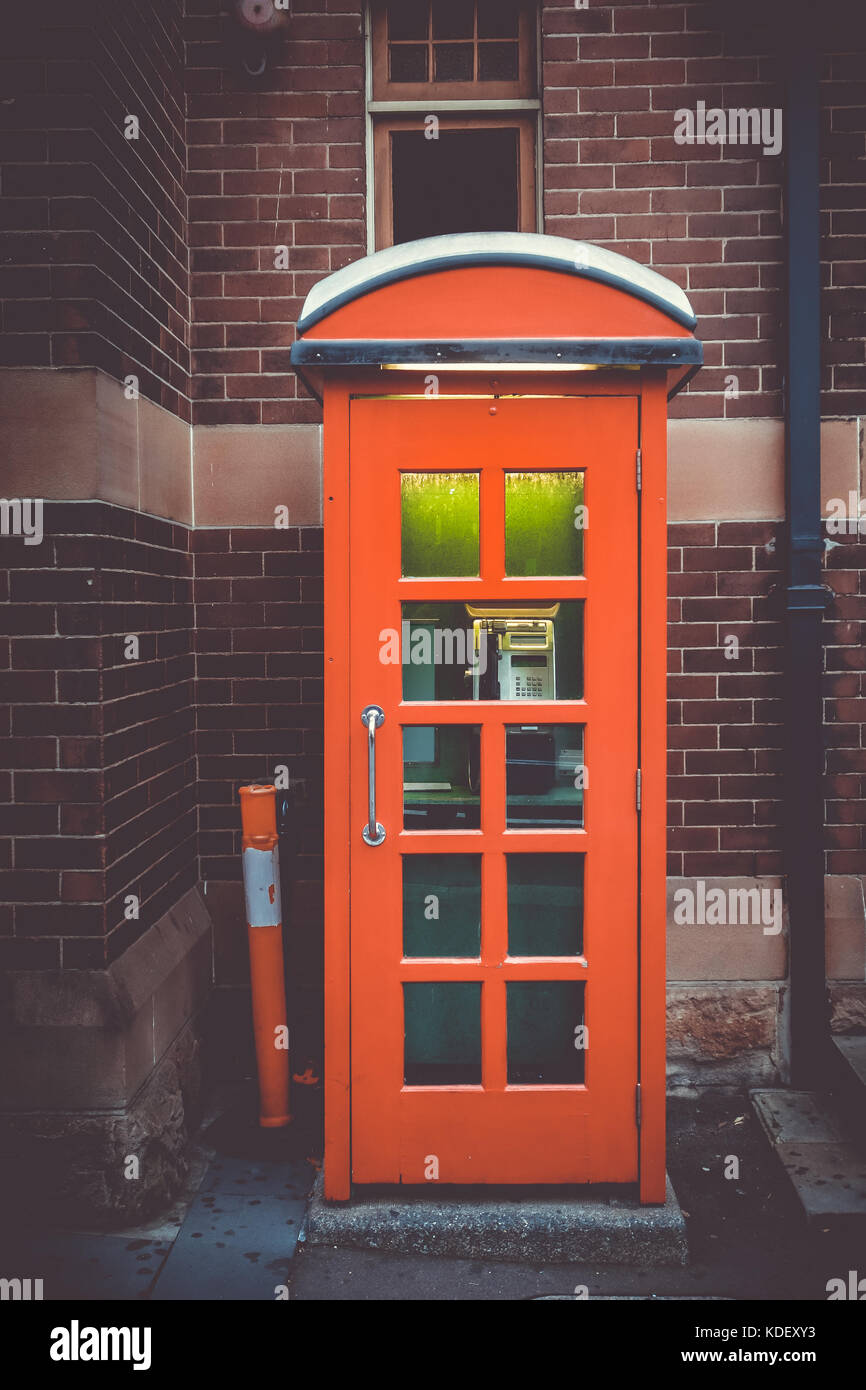 Vintage UK red phone booth in front of a brick wall Stock Photo - Alamy