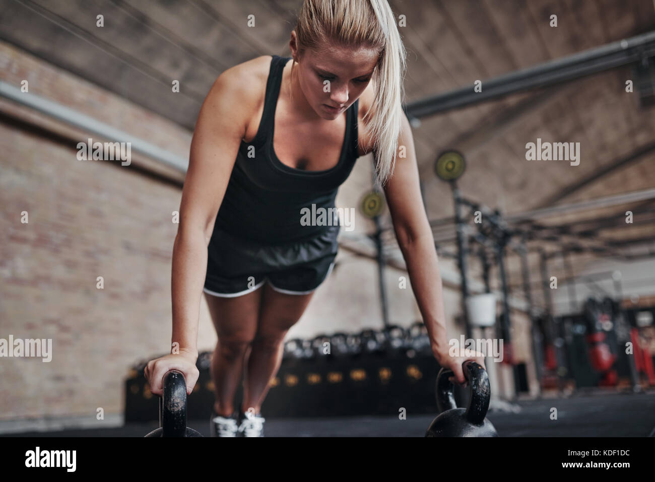 Focused young blonde woman in exercise clothing working out alone with ...
