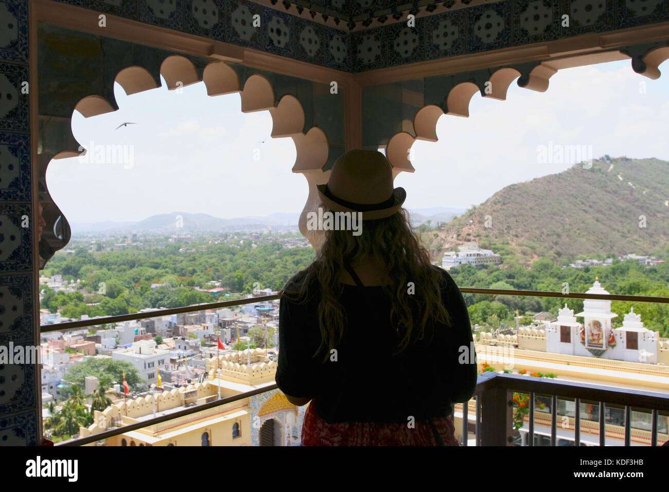 Female traveller looks through a window at the Udaipur City Palace in ...