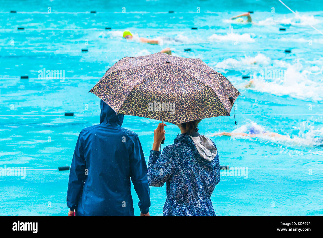 female swimming coaches standing by the swimming pool in the rain ...
