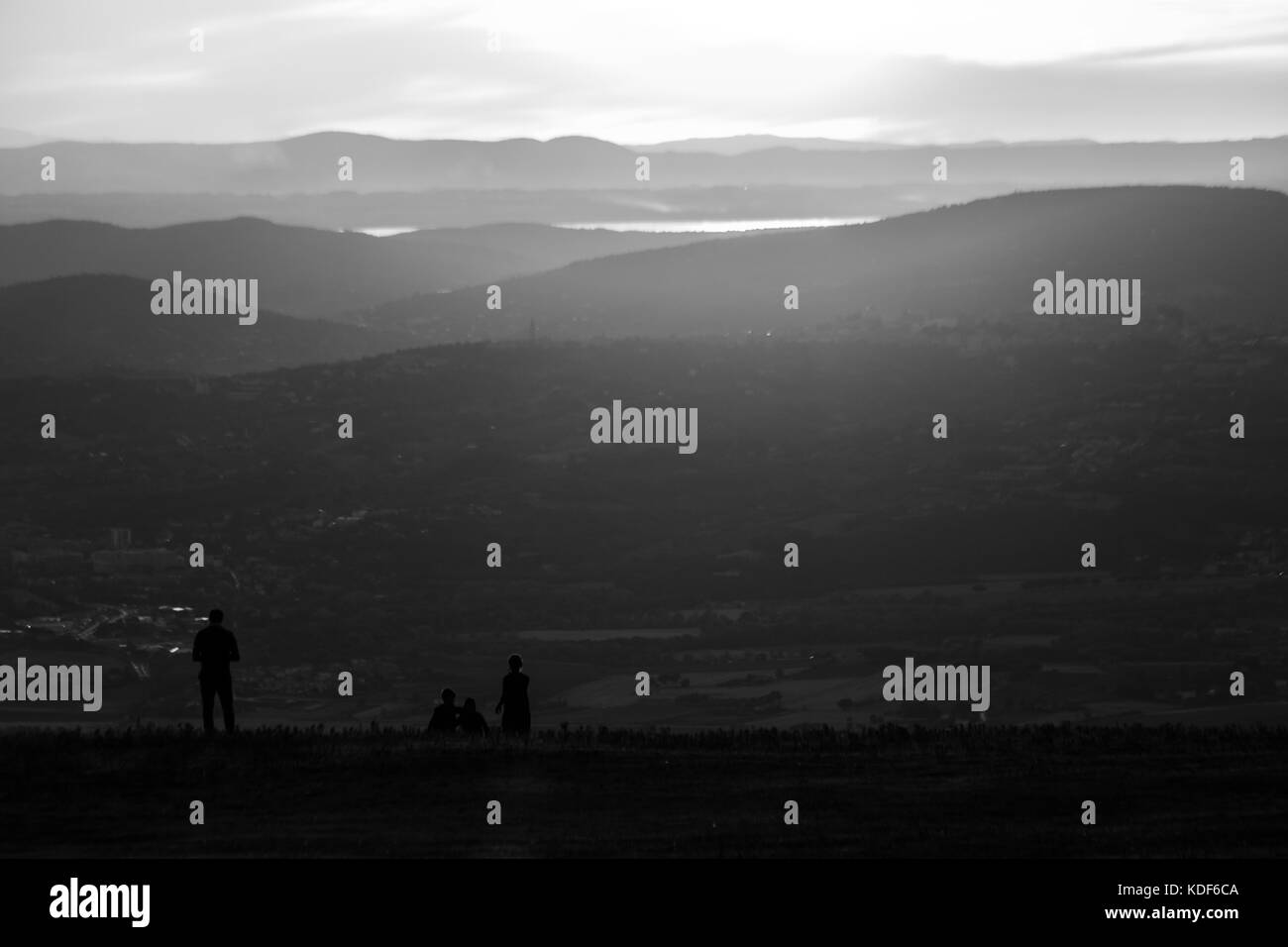 A family on a mountain peak looking over a valley at sunset Stock Photo ...