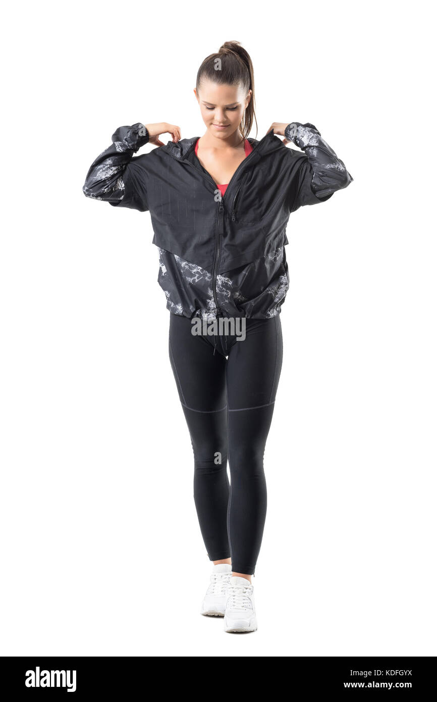 Smiling looking down sporty woman adjusting tracksuit jacket hoodie ...