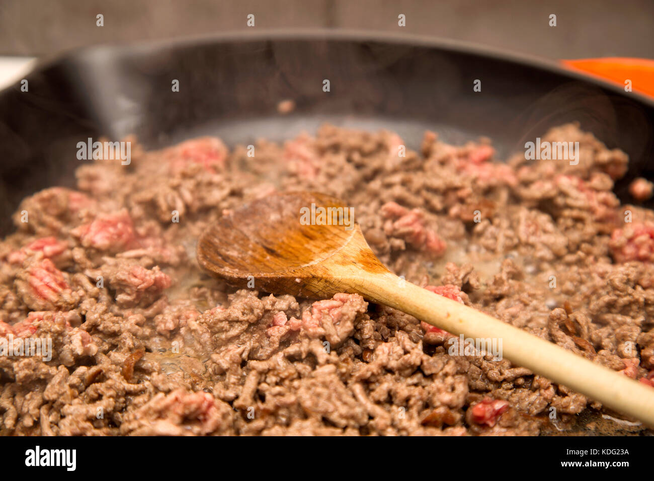 Minced meat being fryed in a pan, wooden spatula lying in the pan and ...