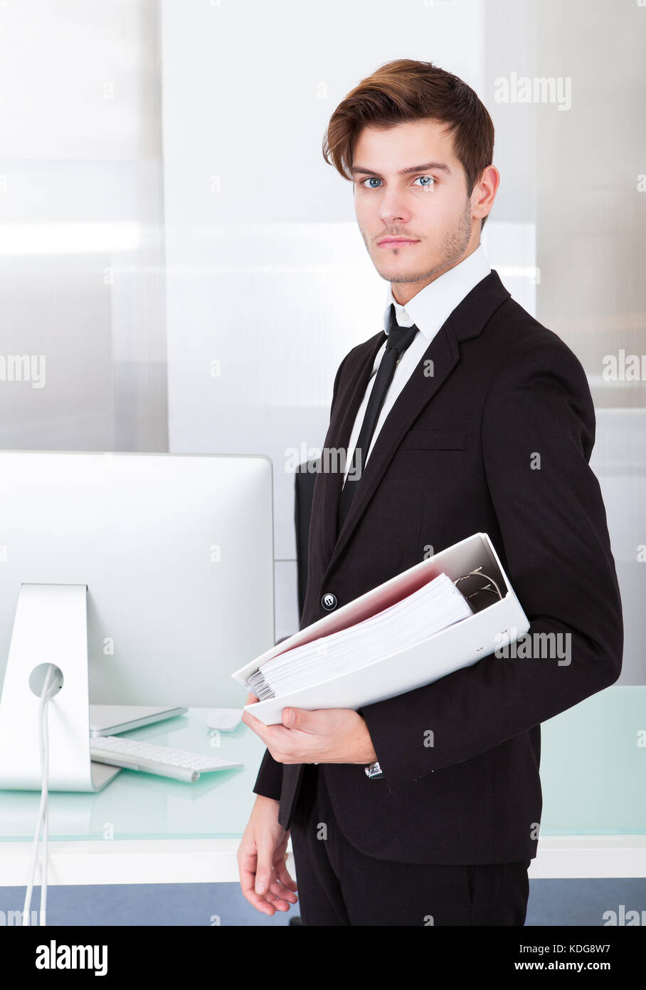 Handsome Young Businessman Holding Folder In Office Stock Photo - Alamy