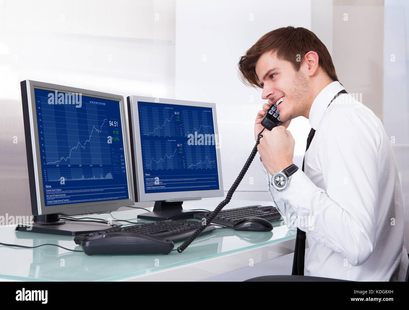 Stock Broker Using Telephone Sitting In Front Of Desktop Stock Photo ...